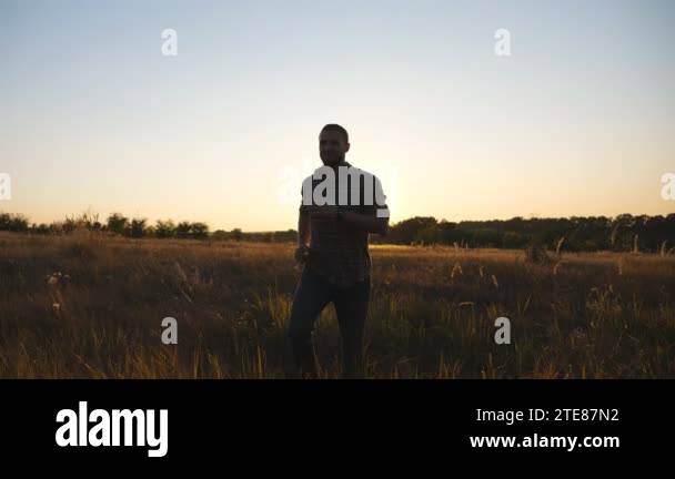 Happy guy running through grass field and victoriously raising hands up ...