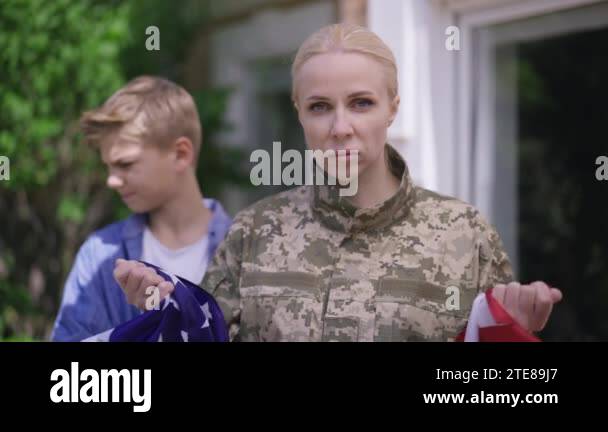Portrait of brave worried woman posing with USA flag as blurred teenage ...