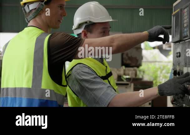 At a manufacturing factory, an industrial engineer operates a control ...