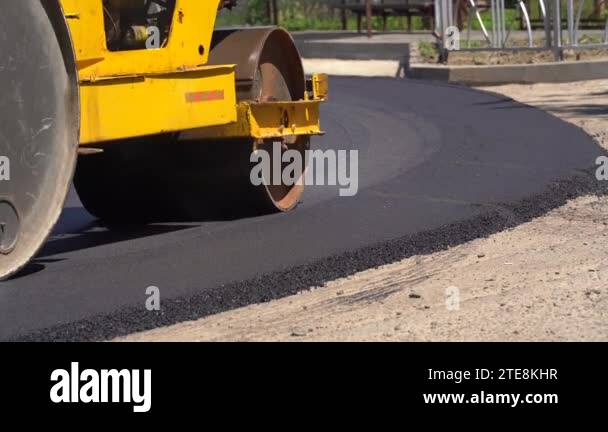 Road roller makes new road. Asphalt paver applying asphalt on a highway ...