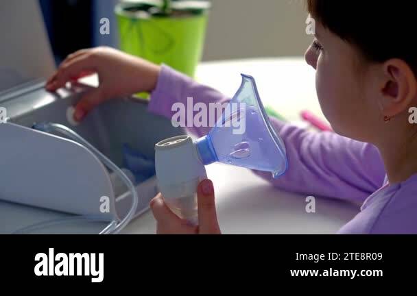 Little girl turn on nebulizer to make inhalation with medical inhaler ...