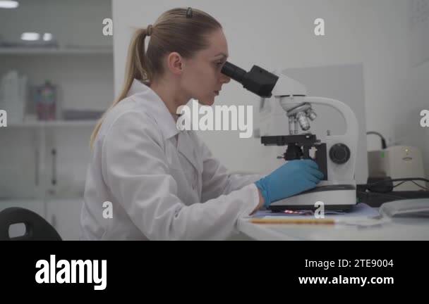 Female medic in uniform working with microscope making analysis at ...