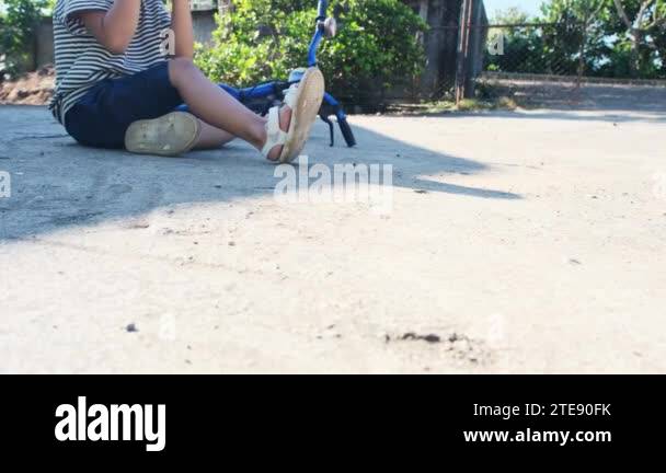 Sad little girl sitting on the ground after falling off her bike at ...