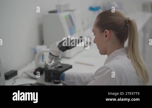 Female medic in uniform working with microscope making analysis at ...