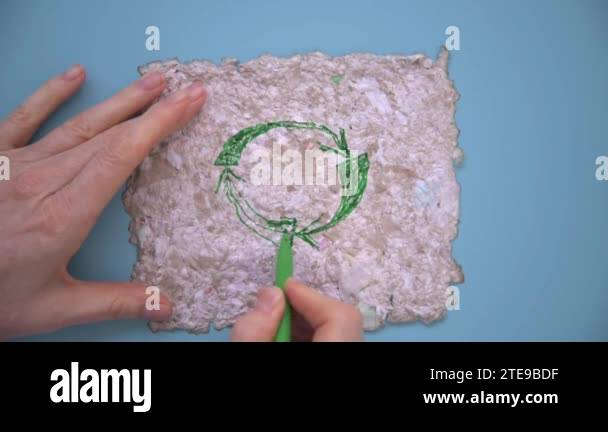 Womens hands draw a sign of reuse with a green felt-tip pen. Drawing on ...