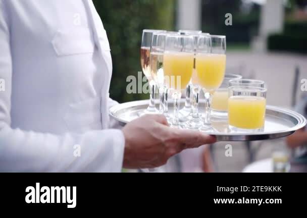 Restaurant waiter in white uniform holding silver tray with filled ...