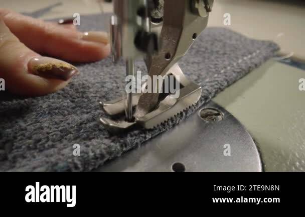 Seamstress sews woolen fabric on sewing machine, advances fabric with ...