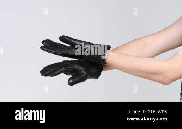 A man wearing black gloves claps his hands with the back of his hand ...