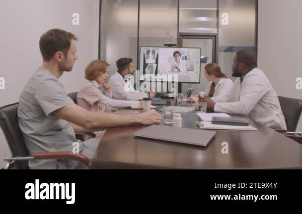 Dollying-in shot of multiethnic medical team sitting around table in ...