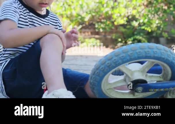 Sad little girl sitting on the ground after falling off her bike at ...