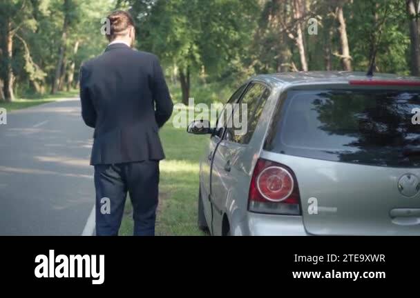 Back view drunken driver walking to car sitting on drivers seat closing ...