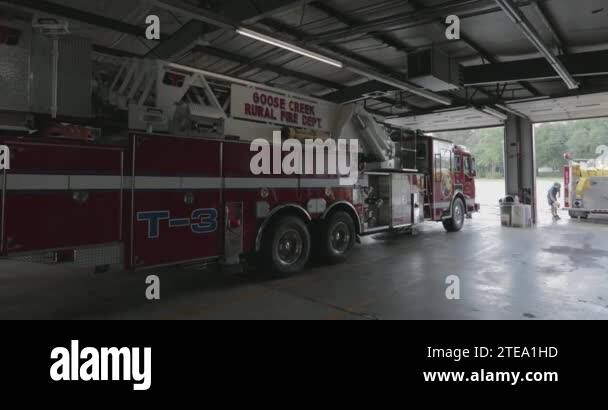 Handheld of fire engine ladder truck sitting inside a fire station as ...