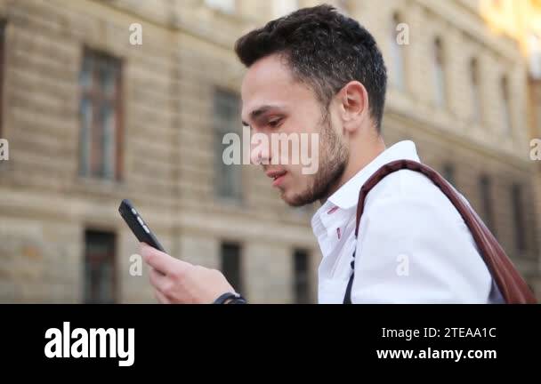 Attractive guy watching on a phone screen and smiling. Positive male in ...
