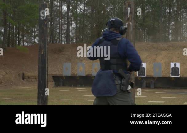 Police officer stands at the firing line at a gun range during target ...