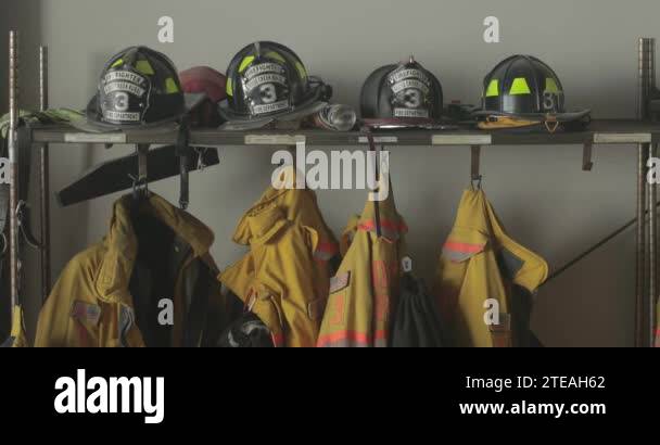 Firefighter helmets and coats hang on an equipment rack at a fire ...