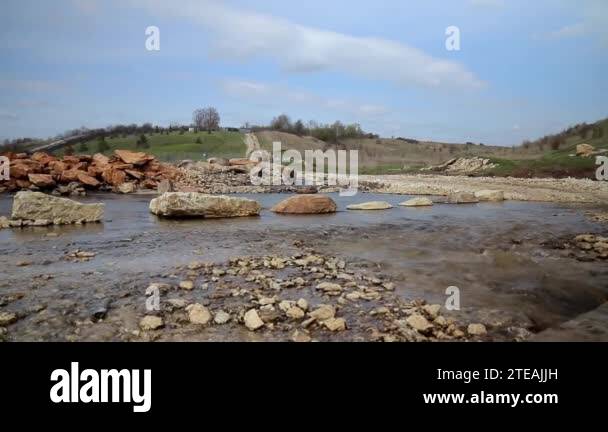 Clear spring water flows over rocks and fall into the river with hills ...