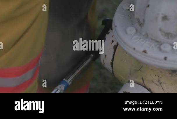 Firefighter removes fire hydrant cap during emergency response for ...