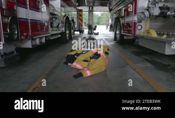 Firefighting gear sits on the floor between two firetrucks inside a ...
