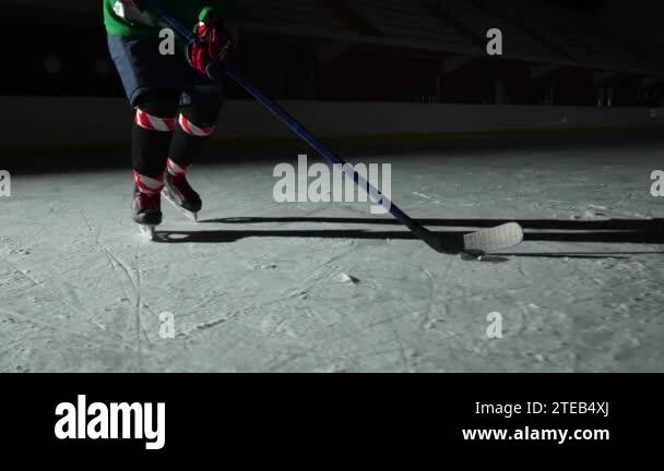 Low angle hockey forward player masterfully dribbles, hitting puck with ...