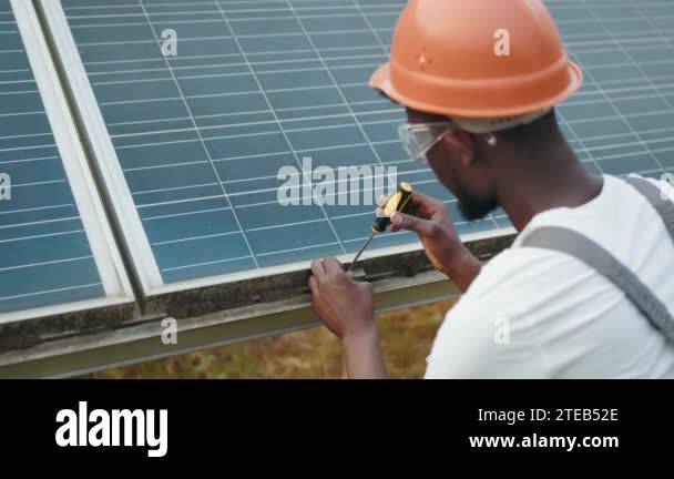 African american technician in helmet and overalls fixing solar panels ...