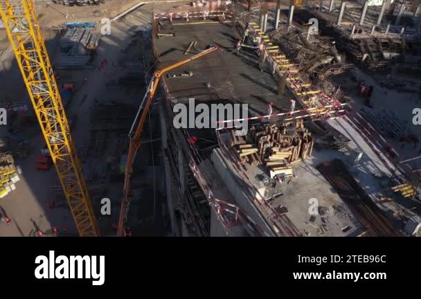 Skilled builders work on roof of large sports arena building near tower ...