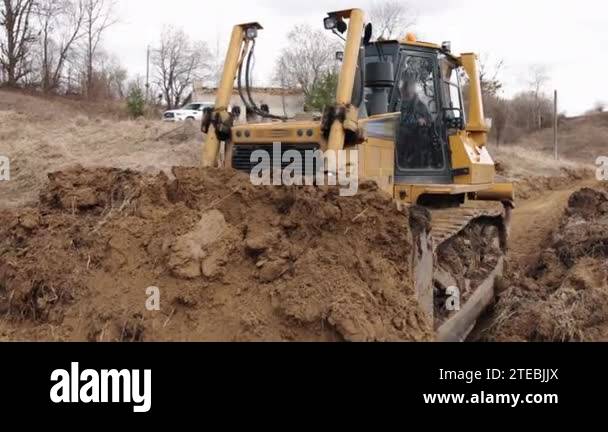 Bulldozer at construction site shovels soil into a heap. Powerful ...