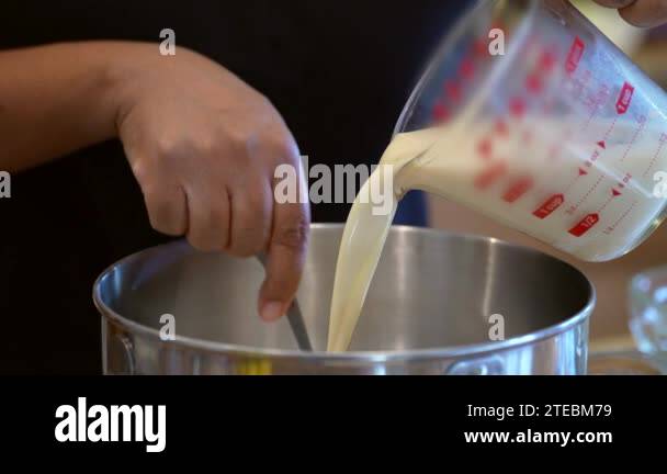 Pouring milk into a mixing bowl to make a tasty homemade treat ...