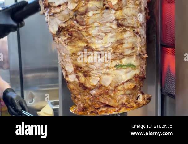 Cutting meat with a special knife from a vertically rotating skewer ...