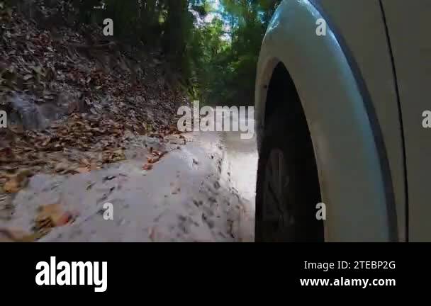 POV view past the front wheel of a white 4WD offroad truck from a car ...