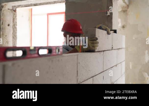 Bricklayer or mason lays bricks to construct wall of autoclaved aerated ...
