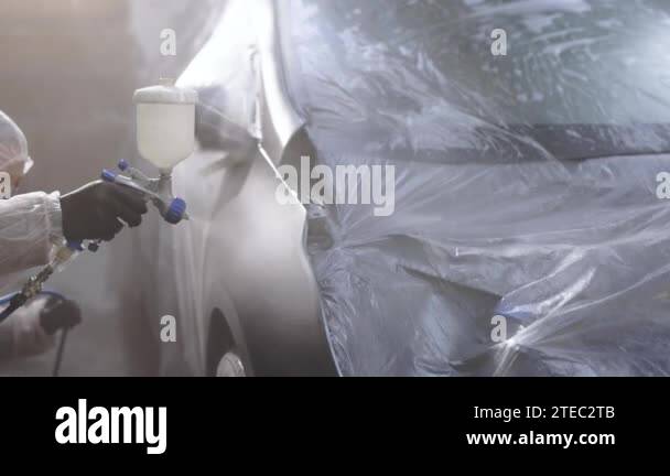 Male technician is air-painting cars wing. Industrial spray painting ...