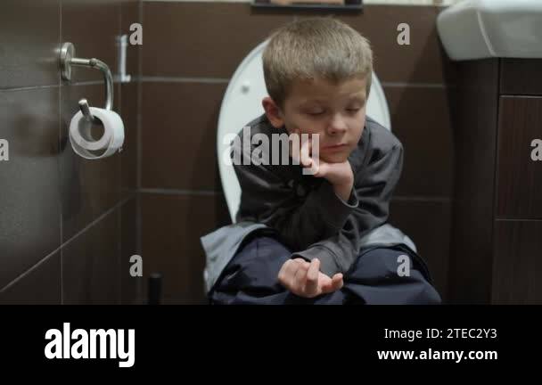 a boy sits on the toilet in the restroom Stock Video Footage - Alamy