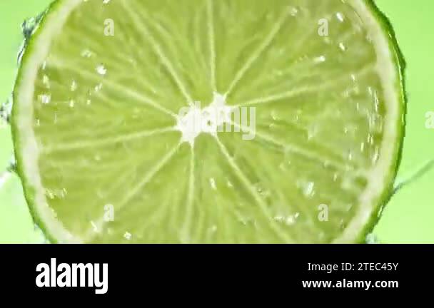 Super Slow Motion of Lime Slice With Water Splashes. Rotating Slice of ...