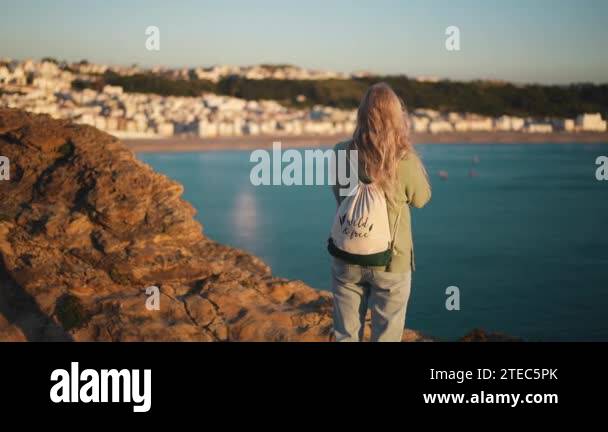 Woman traveler at rocks of Fort of Sao Miguel Arcanjo, town of Nazare ...