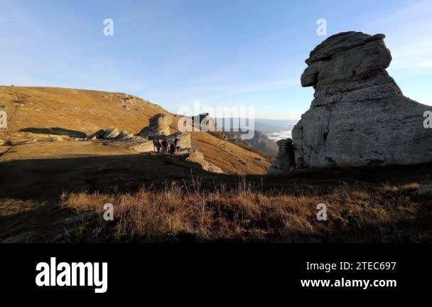 People on the top of a mountain stand near by large cliff shooting the ...