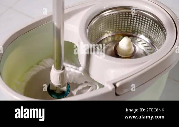 Woman holding mop with microfiber head spinning water in the bucket ...