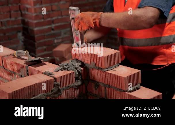 The process of building a brick wall. The builder is laying the bricks ...