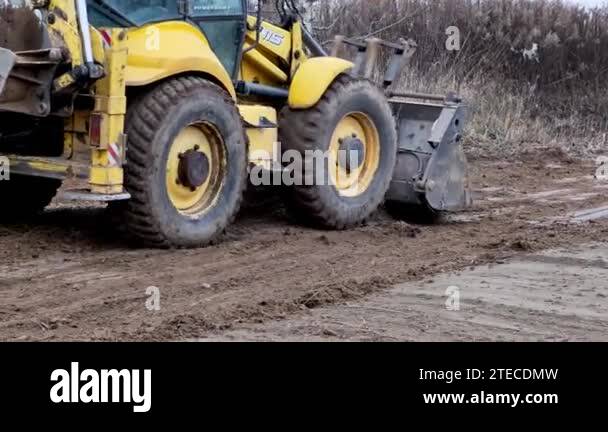 Tractor levels field. Backhoe loader clearing construction site ...