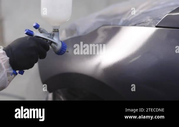 Close up of male workers in safety wear during painting car. Industrial ...