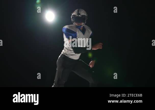 American football player wearing uniform, pads and helmet catches pass ...