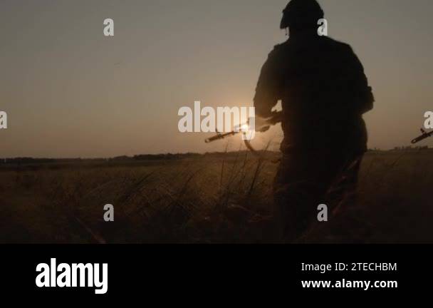 Two armed men with weapon walking across field after combat operation ...