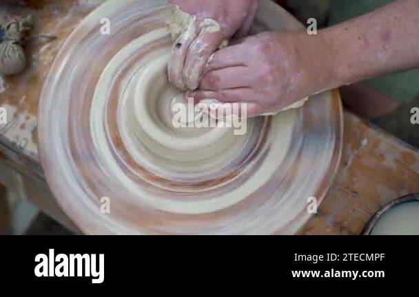 A rotating potters wheel and pottery on it, shot from above. A man ...