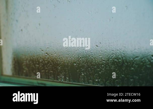 Raindrops fall on the window and window sill, flowing down. Rainy ...