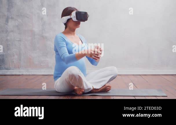 Young pregnant woman in VR helmet. She is preparing for the birth of a ...