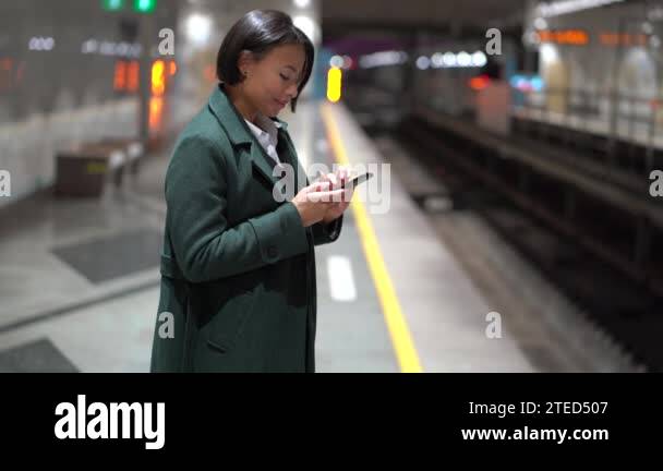 Smiling afro woman at subway platform with smartphone, black female ...