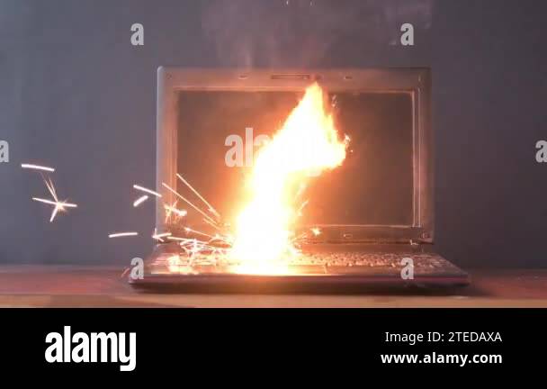 In the room on the table, a laptop caught fire, flames and sparks, a ...
