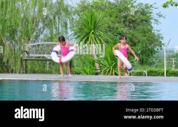 Happy little sisters with rubber ring in swimming pool. Kids play in ...