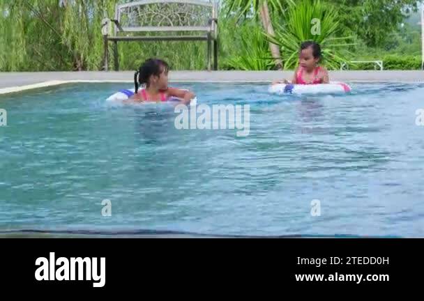 Happy little sisters with rubber ring in swimming pool. Kids play in ...