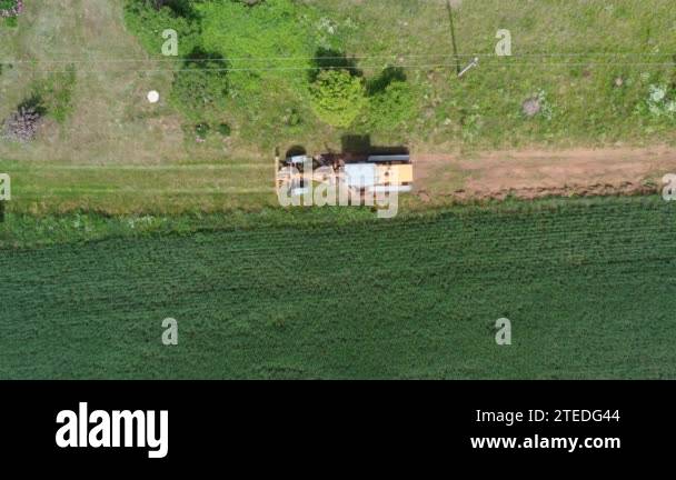 Road leveling grader tractor on bad rural road at work, aerial view ...