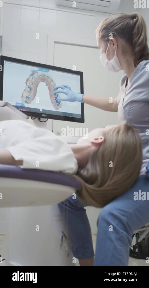 Girl doctor dentist demonstrates a 3D model of teeth on a touch monitor ...